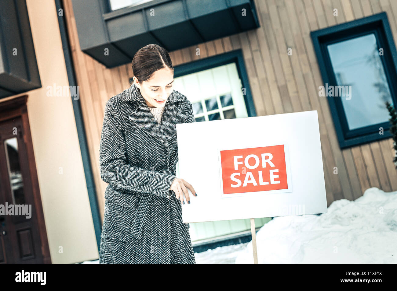 Dark-haired professional real estate agent putting for sale sign Stock ...
