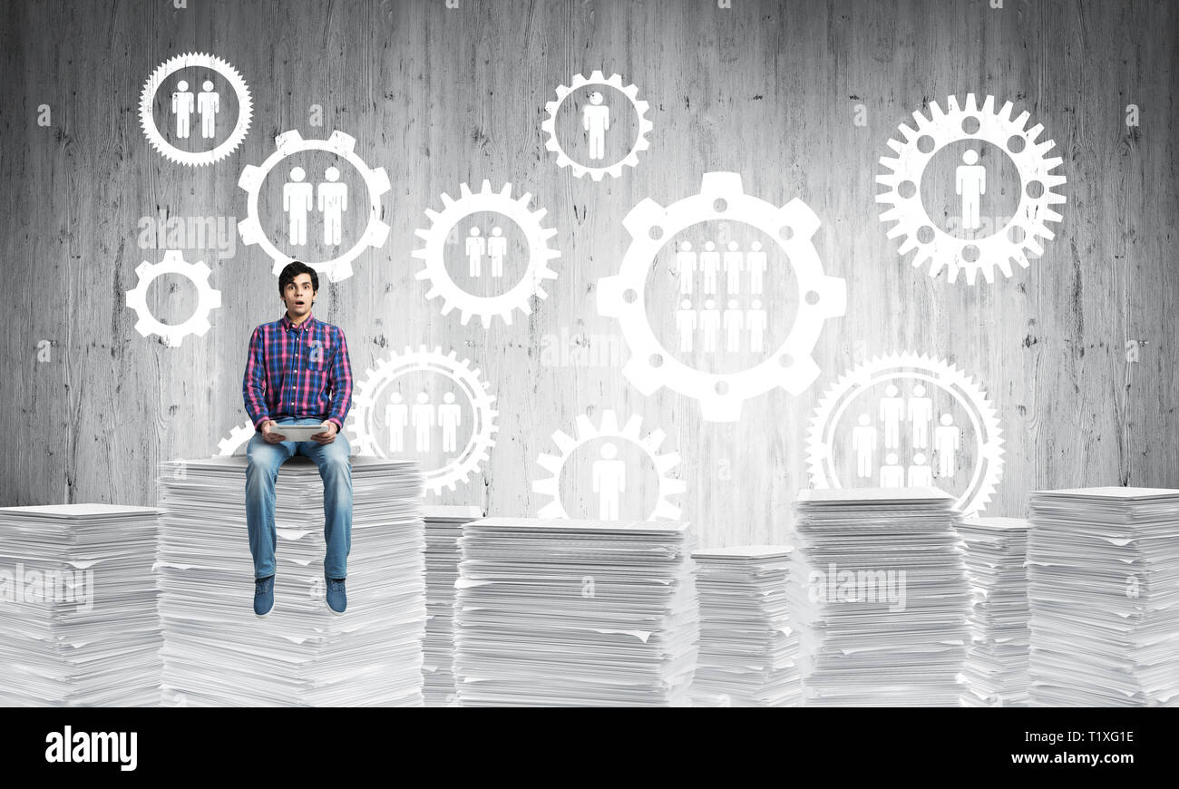 Attractive man sitting on pile of paper documents Stock Photo - Alamy