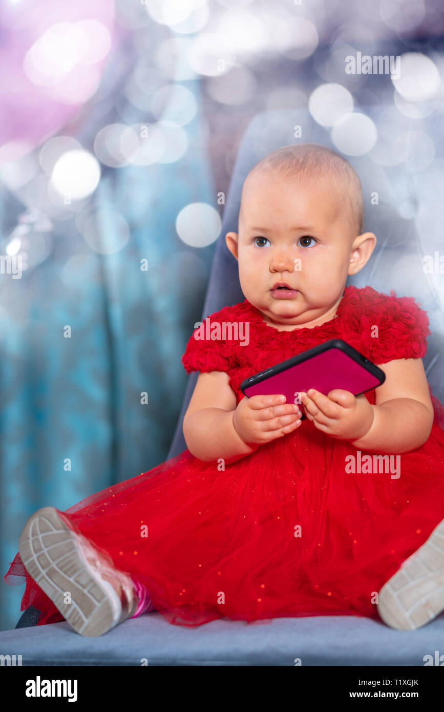 Little baby girl in a colorful red dress celebrating her first birthday ...