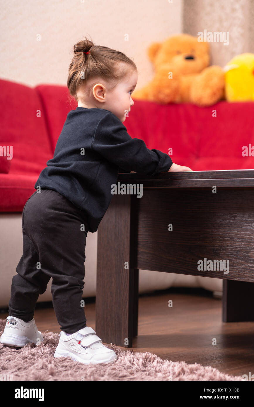 Adorable little baby girl learning to stand balancing holding on to a ...