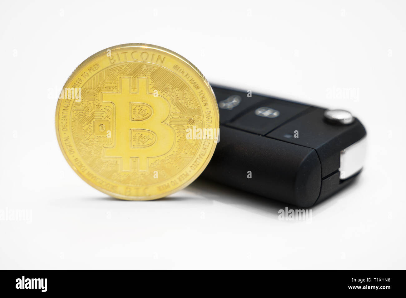 Golden physical bitcoin and car key on white background Stock Photo - Alamy