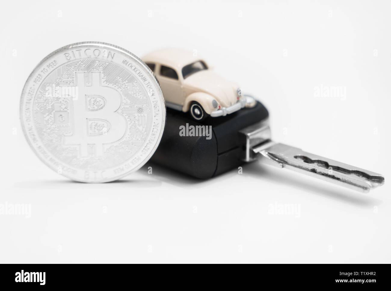 Silver physical bitcoin and car key on white background Stock Photo - Alamy