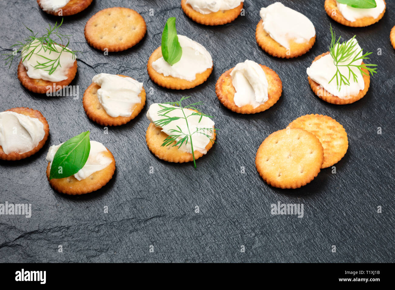 A photo of salt crackers with soft cream cheese spread and herbs on a ...