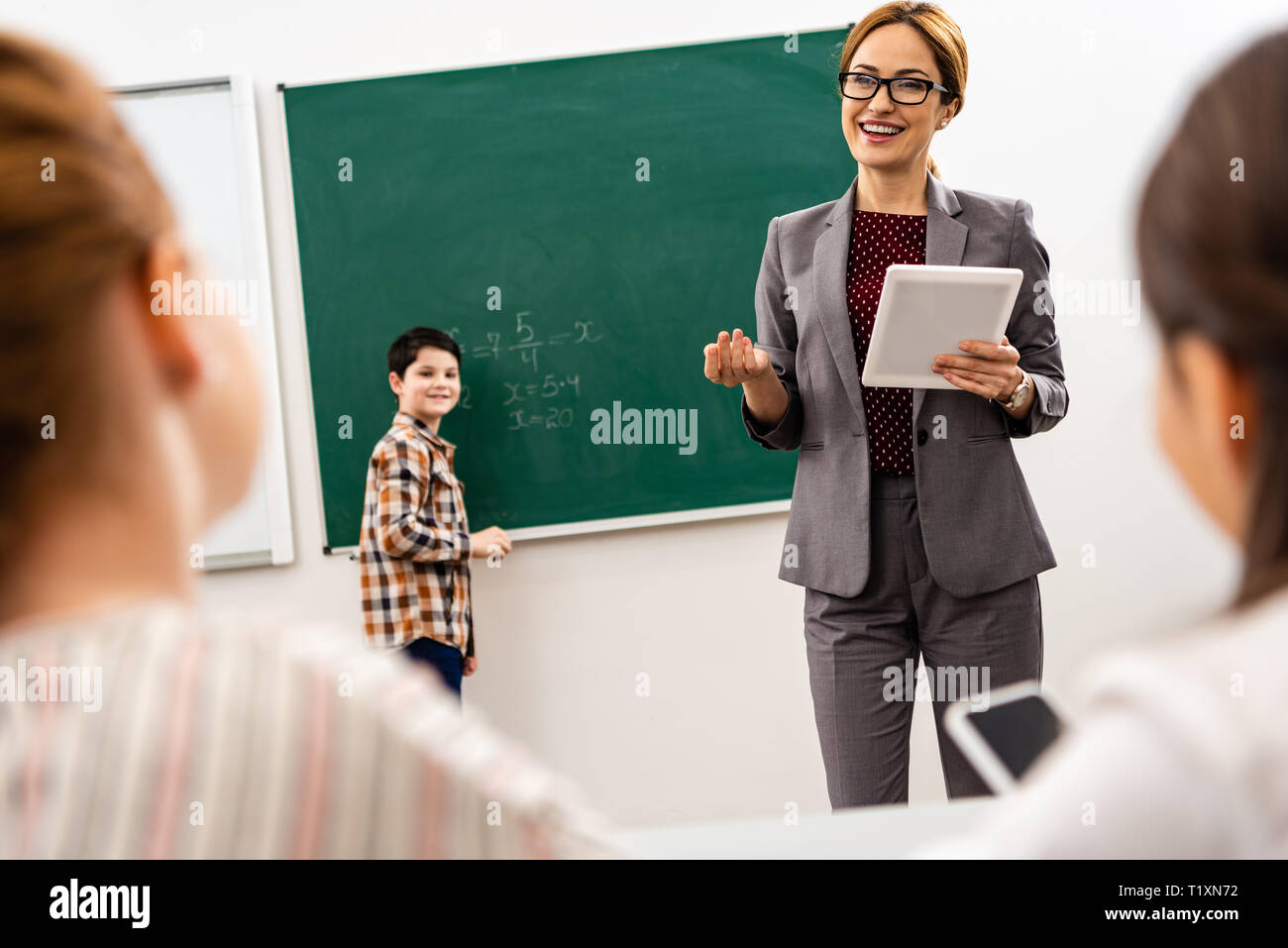 Pupil writing on blackboard with chalk during math lesson Stock Photo ...