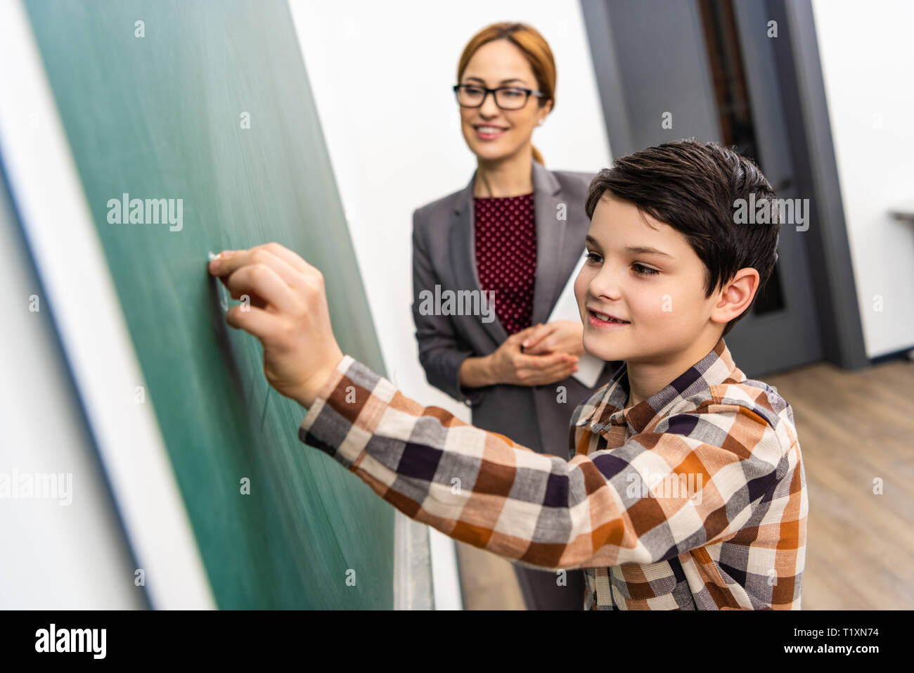 Pupil writing on blackboard with chalk during lesson in classroom Stock ...