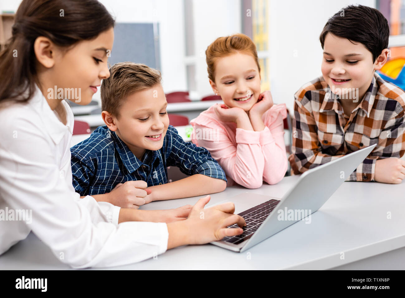 Happy preteen pupils using laptop in classroom with smile Stock Photo ...