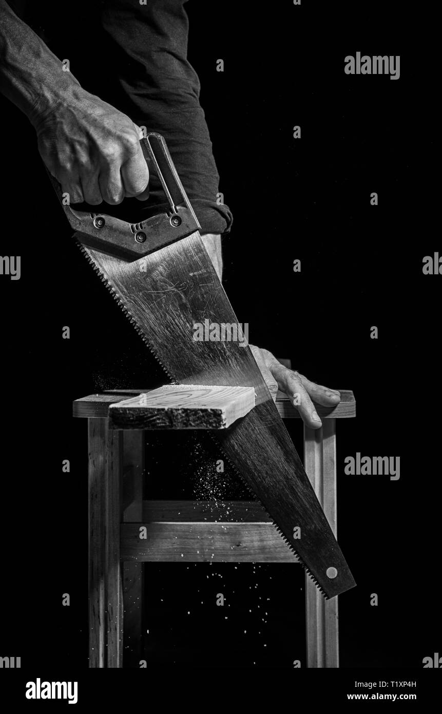 Man sawing a board with a hand saw in black and white Stock Photo - Alamy