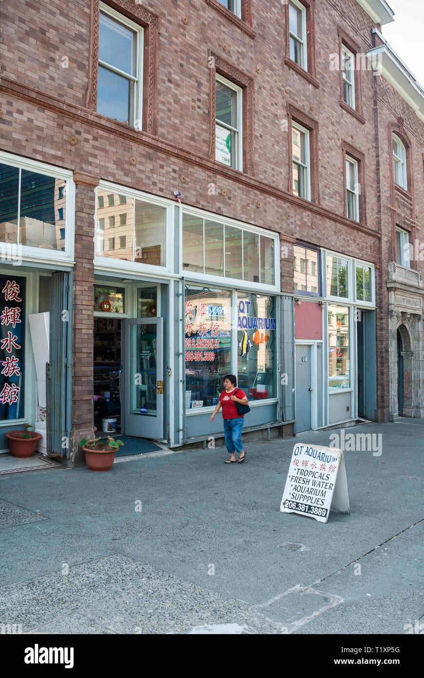 An Asian woman walks on a sidewalk along storefronts in the Seattle ...