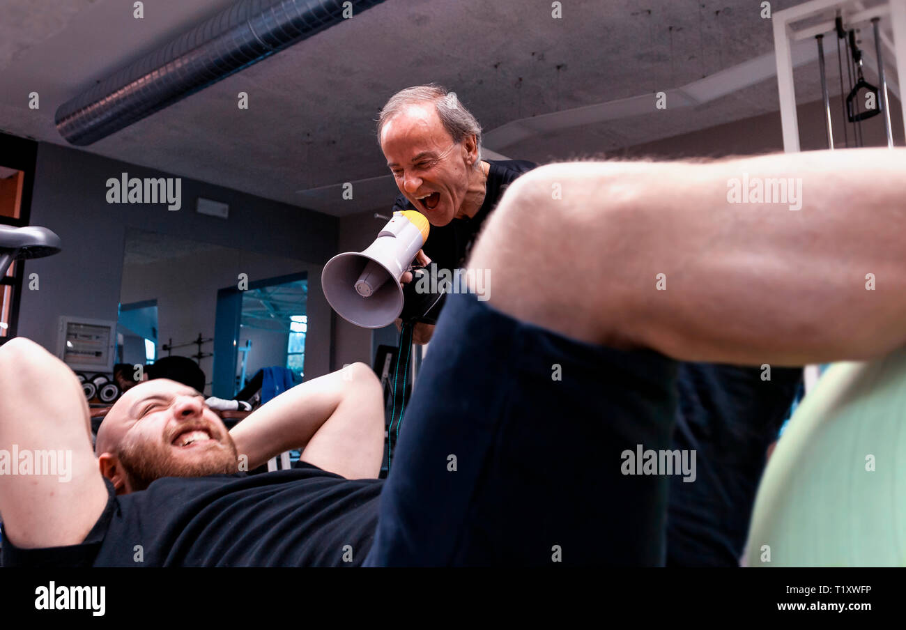 senior trainer screaming with a megaphone at the young athlete while ...