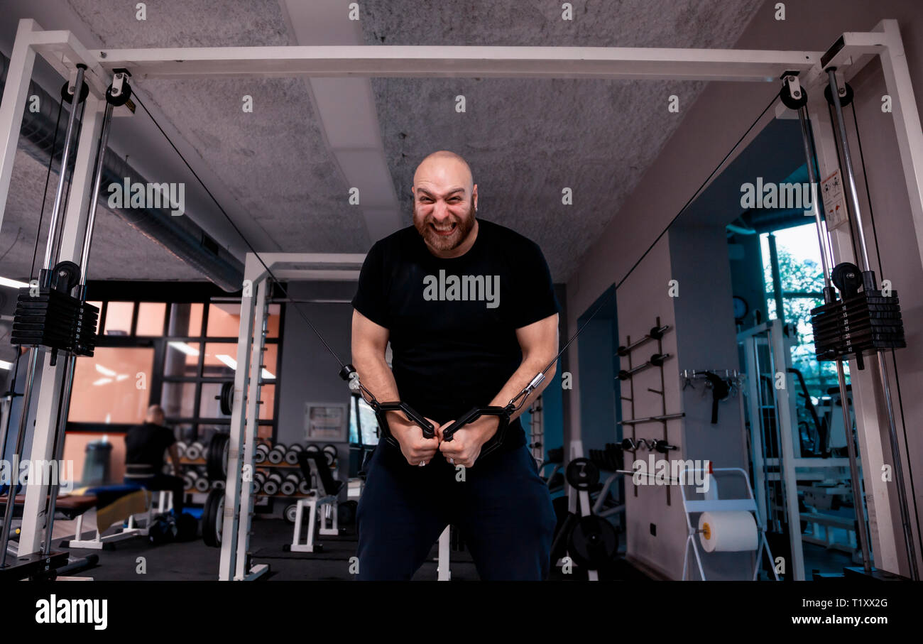 athlete while doing heavy exercises at the cables in the gym Stock ...