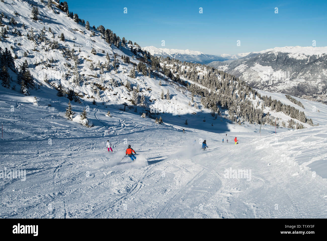 Panoramic landscape valley view with skiers going down a ski slope ...
