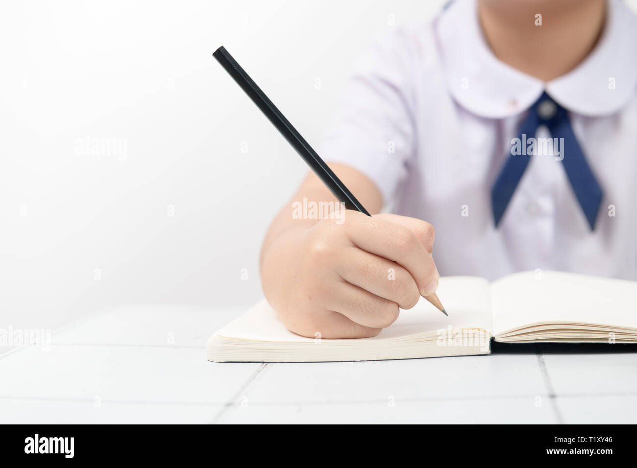Close-up of writing hands of uniform students on white background ...
