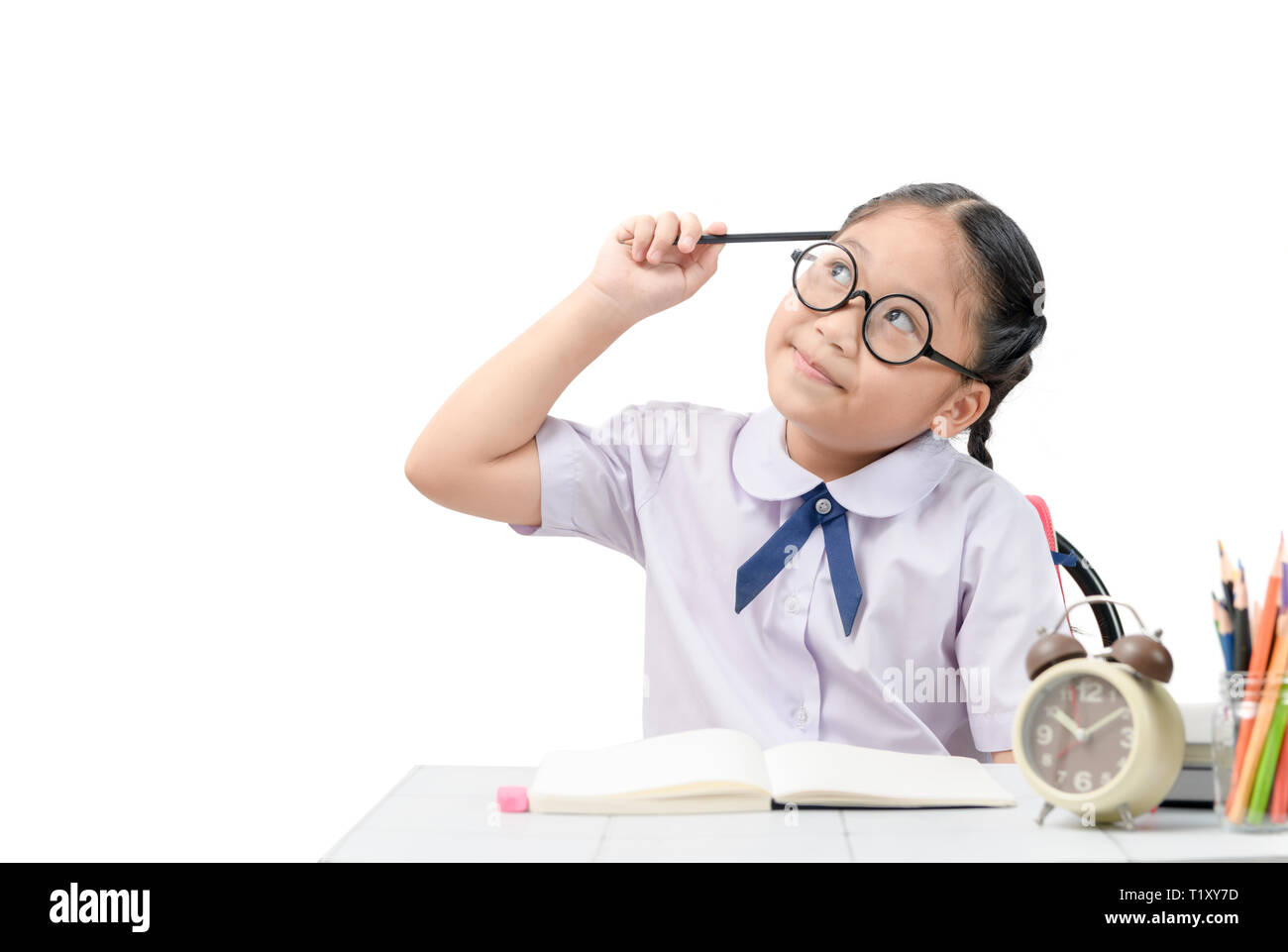 Cute student thinking while doing her homework on table isolated on ...
