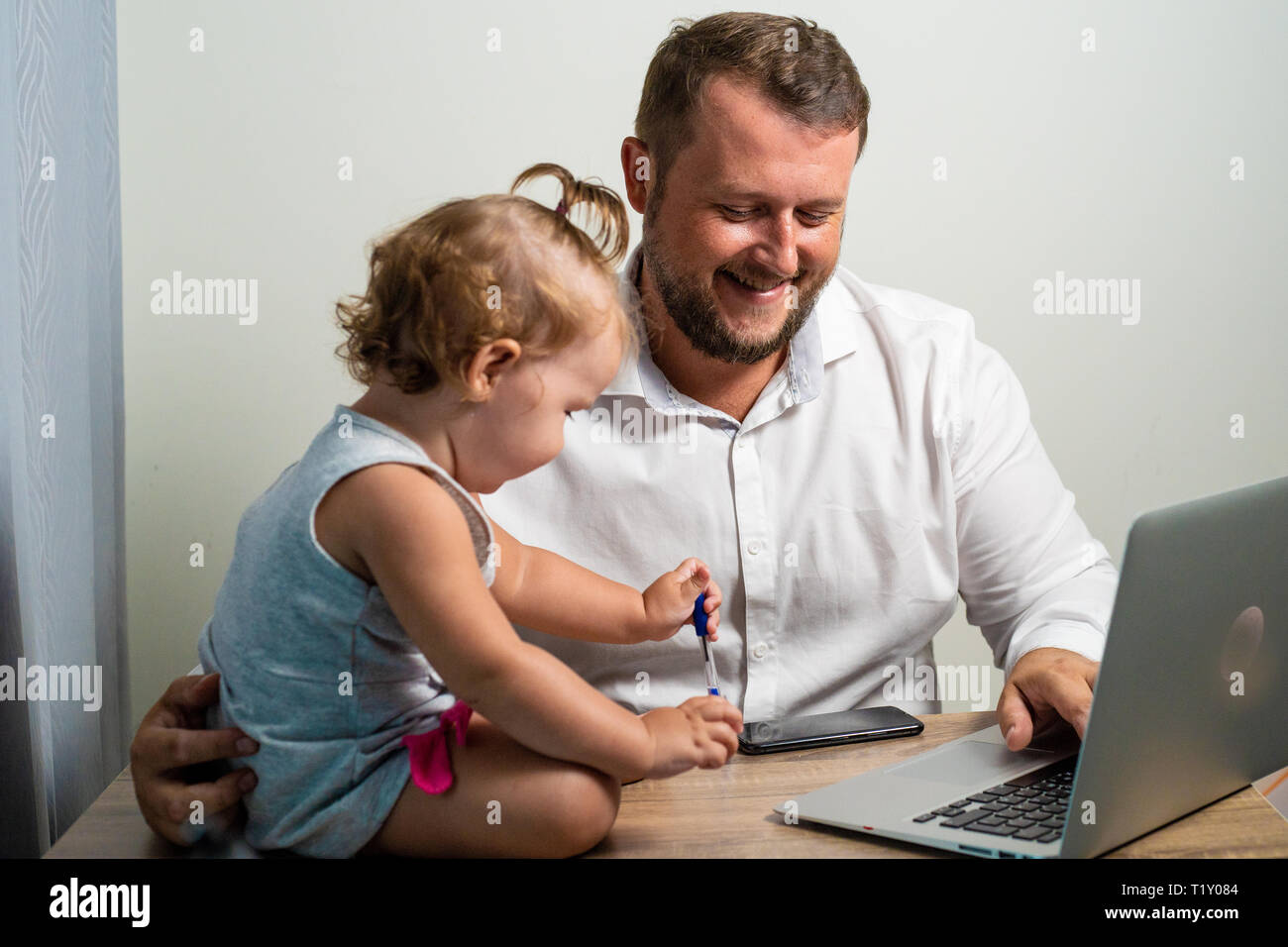 Freelancer work concept. Happy dad working at home with a laptop ...