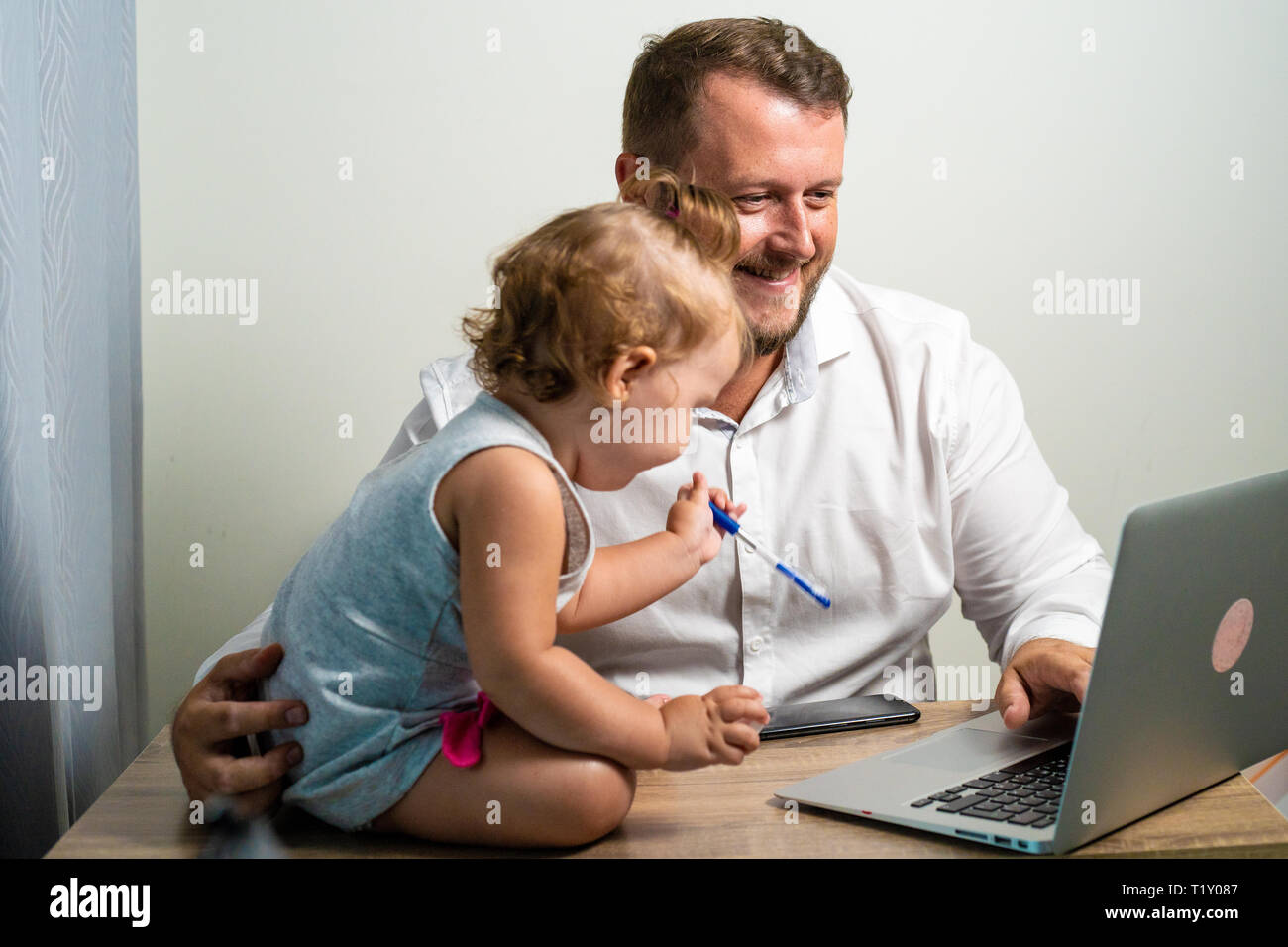 Freelancer work concept. Happy dad working at home with a laptop ...