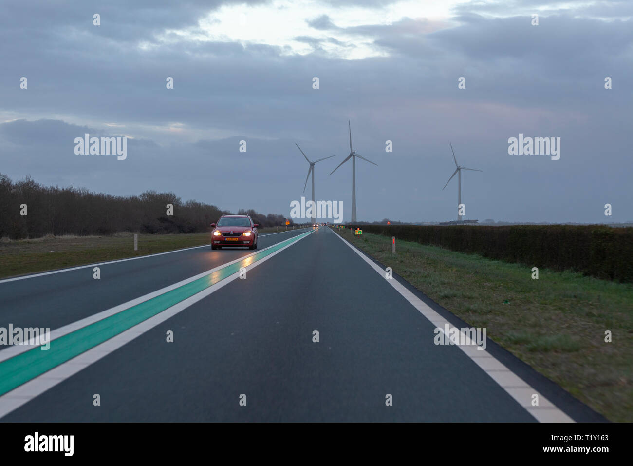 Car moving on a modern road with wind turbines in background ...