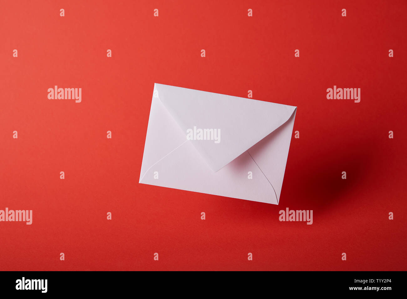 white and empty envelope on colorful red background with copy space ...