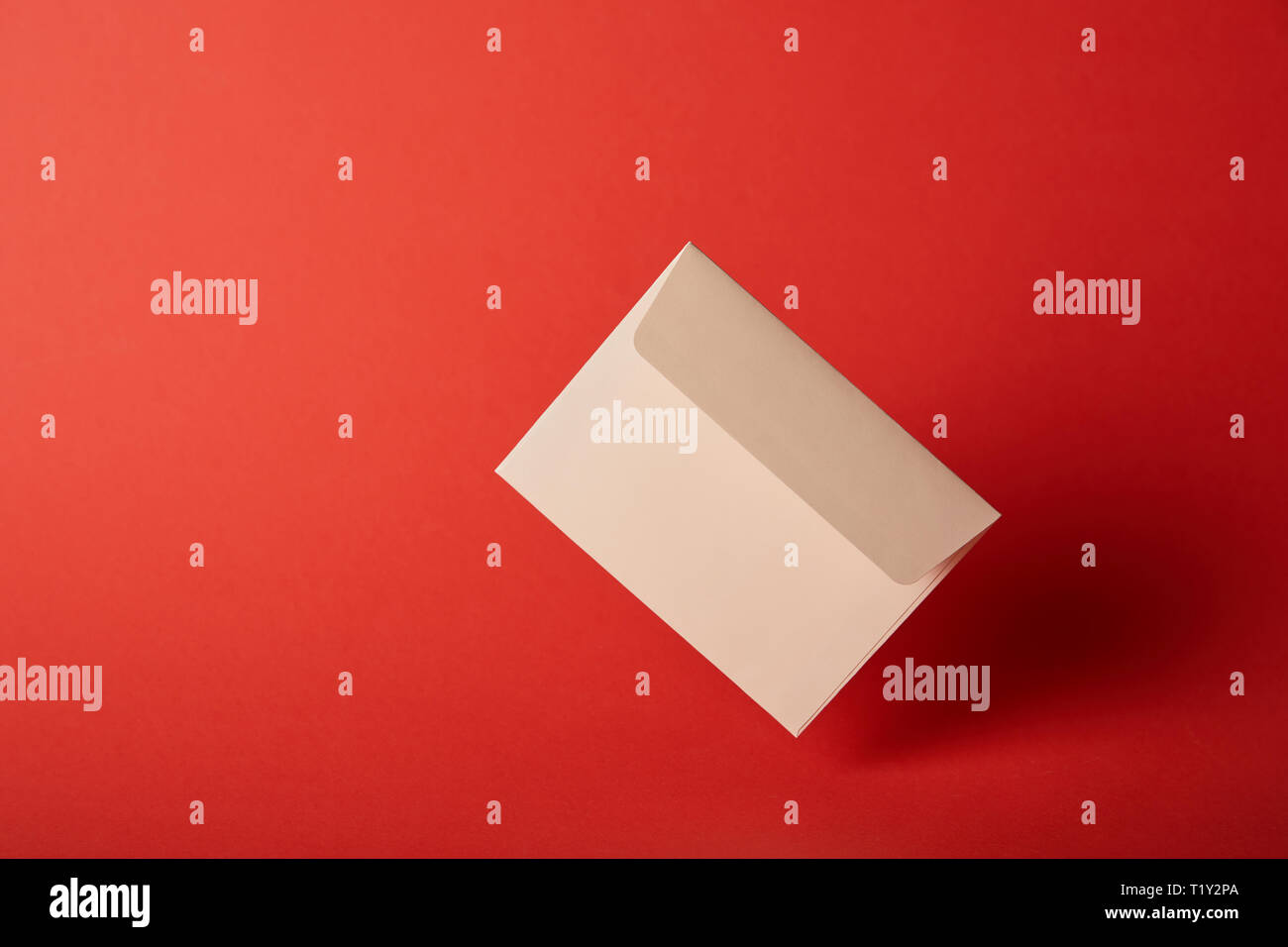 beige, blank and empty envelope on colorful red background with copy ...
