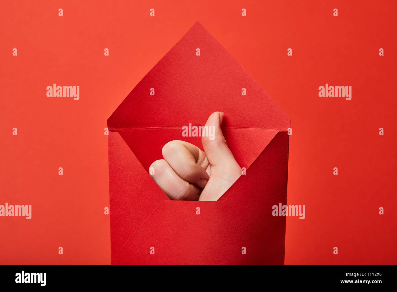 partial view of man showing thumb up in bright envelope on red ...