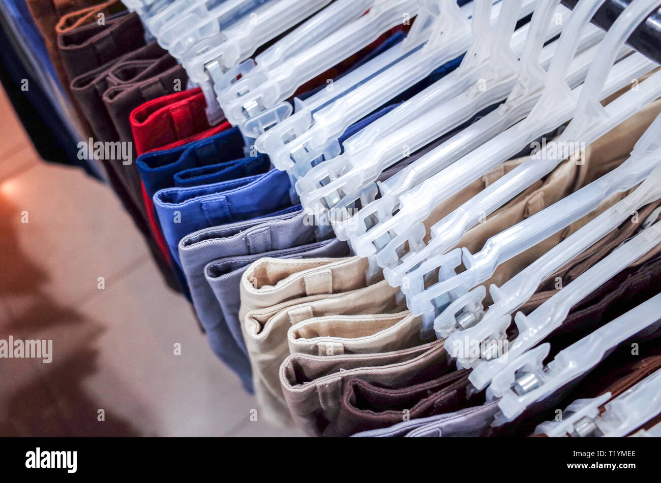Multi colored clothing hanging on hangers Stock Photo - Alamy