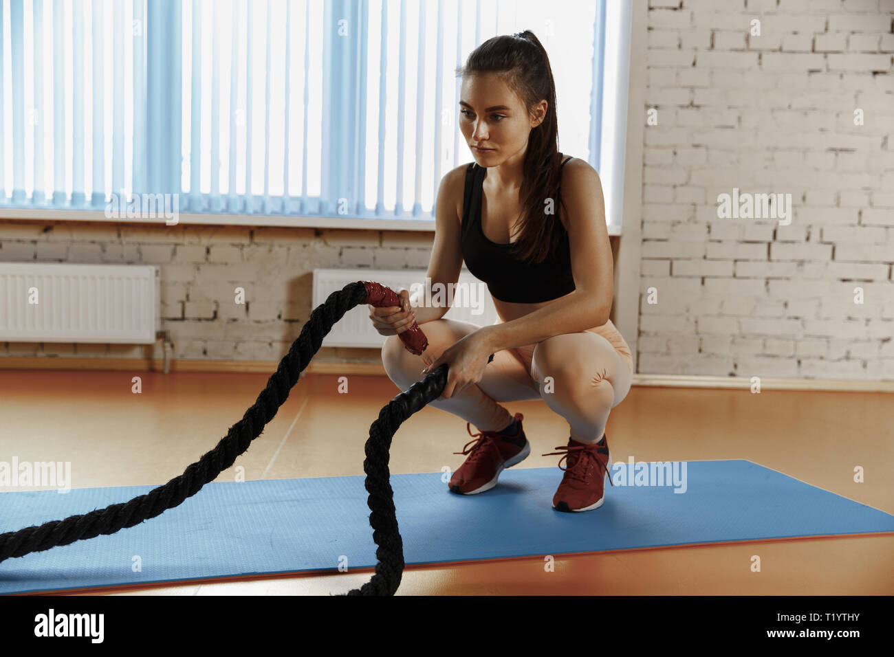 Woman with battle ropes exercise in the fitness gym. Athlete, sport ...
