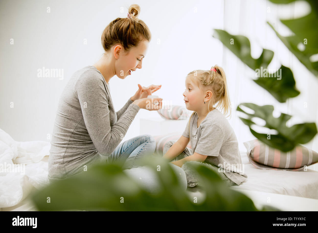 Young mother and her little daughter at home at sunny morning. Soft ...