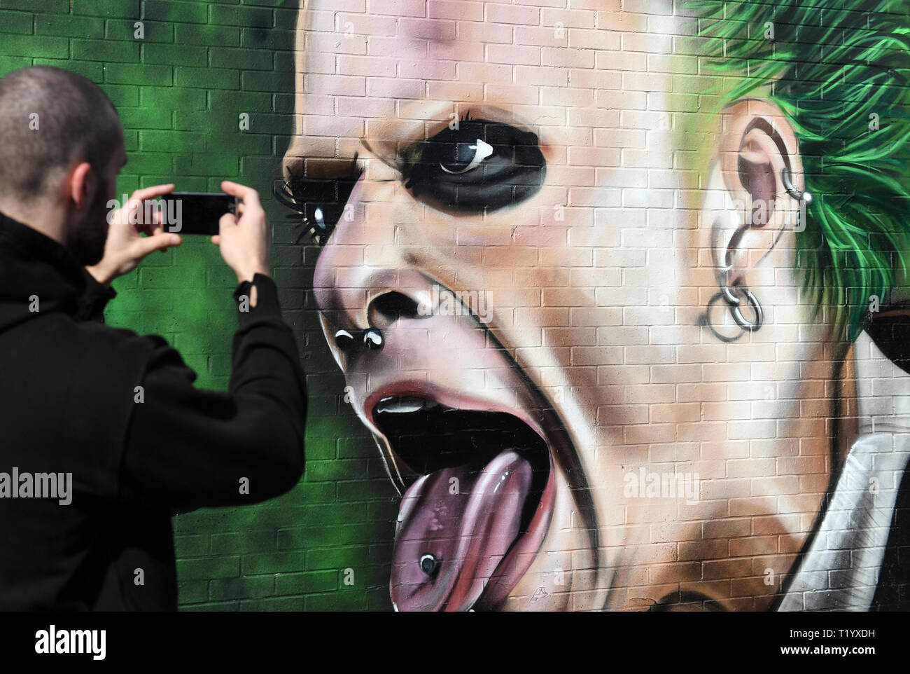 A man takes a photo of a Keith Flint mural of Keith Flint in ...