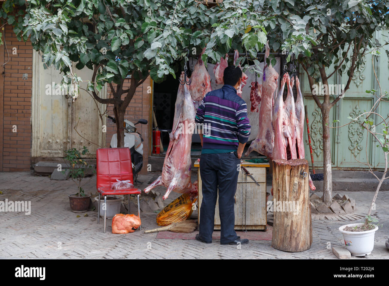Customer considering to buy lamb meat at a butcher in Kashgar (Xinjiang ...