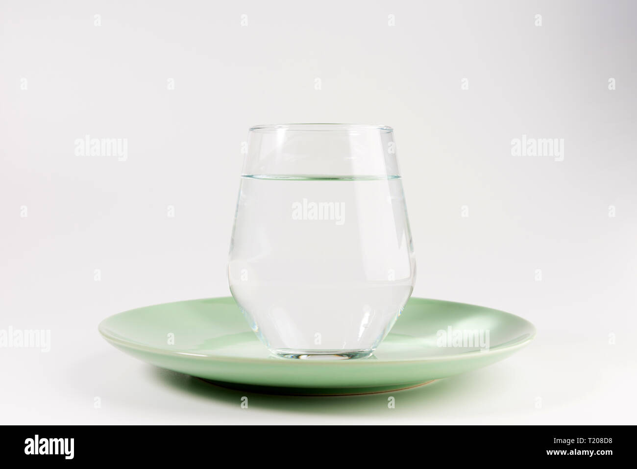 glass of water in a plate isolated on white background Stock Photo - Alamy