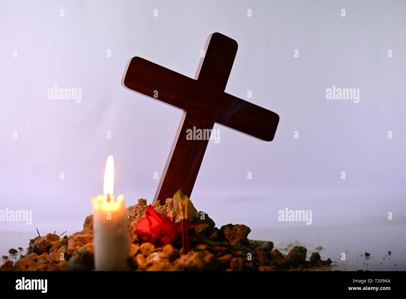 Burning candle under Jesus cross in cemetery isolated against white ...