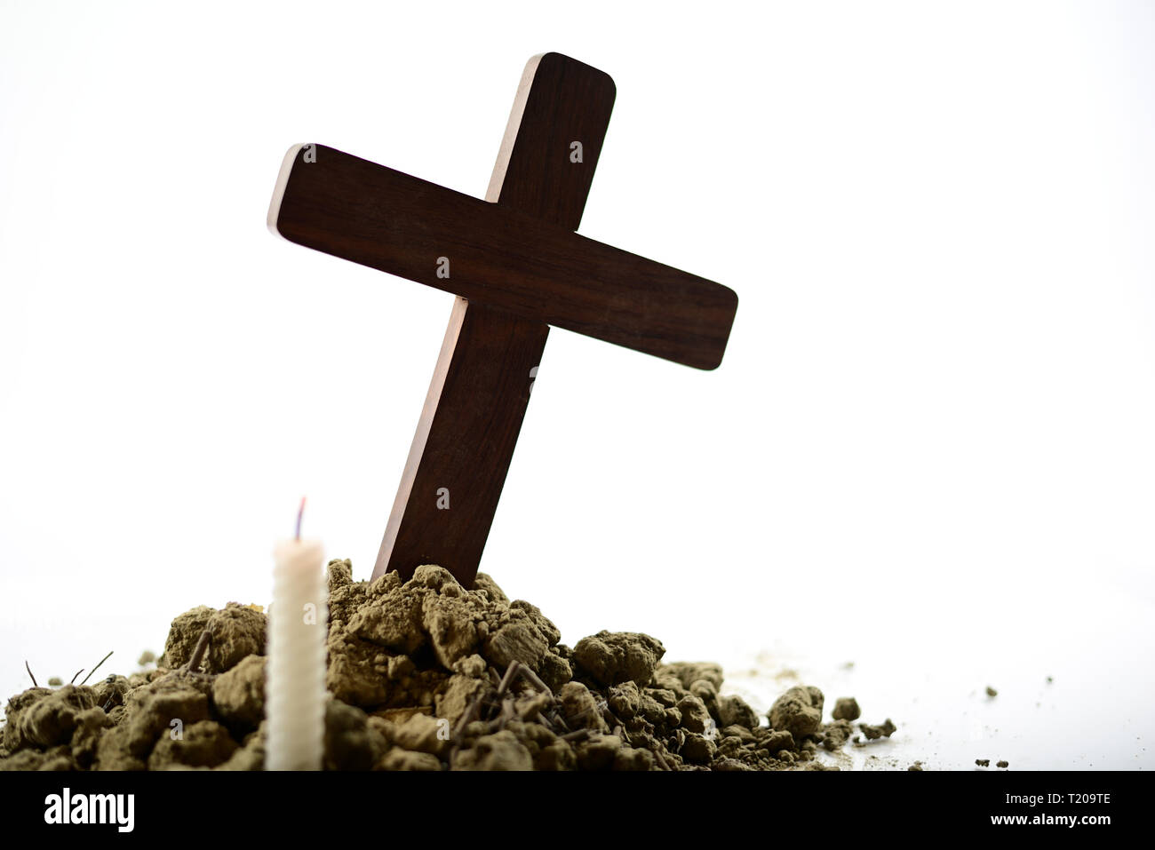 Burning candle under Jesus cross in cemetery isolated against white ...