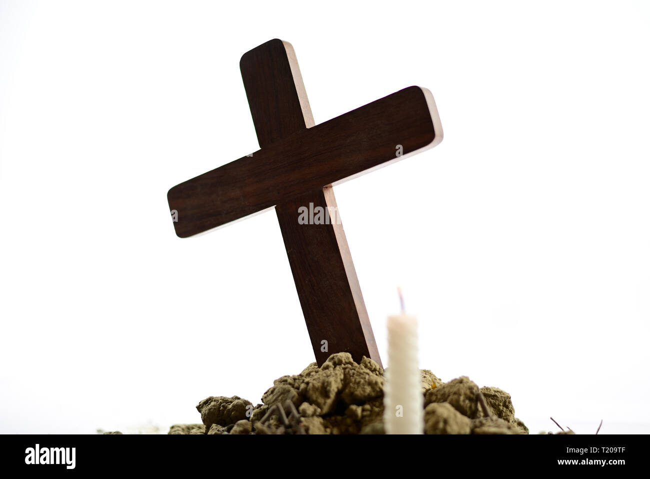 Burning candle under Jesus cross in cemetery isolated against white ...