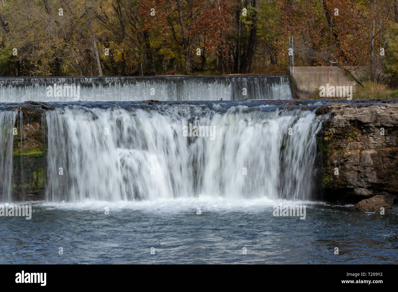 Water flows gracefully over the dam then over the rock ledge splashing ...