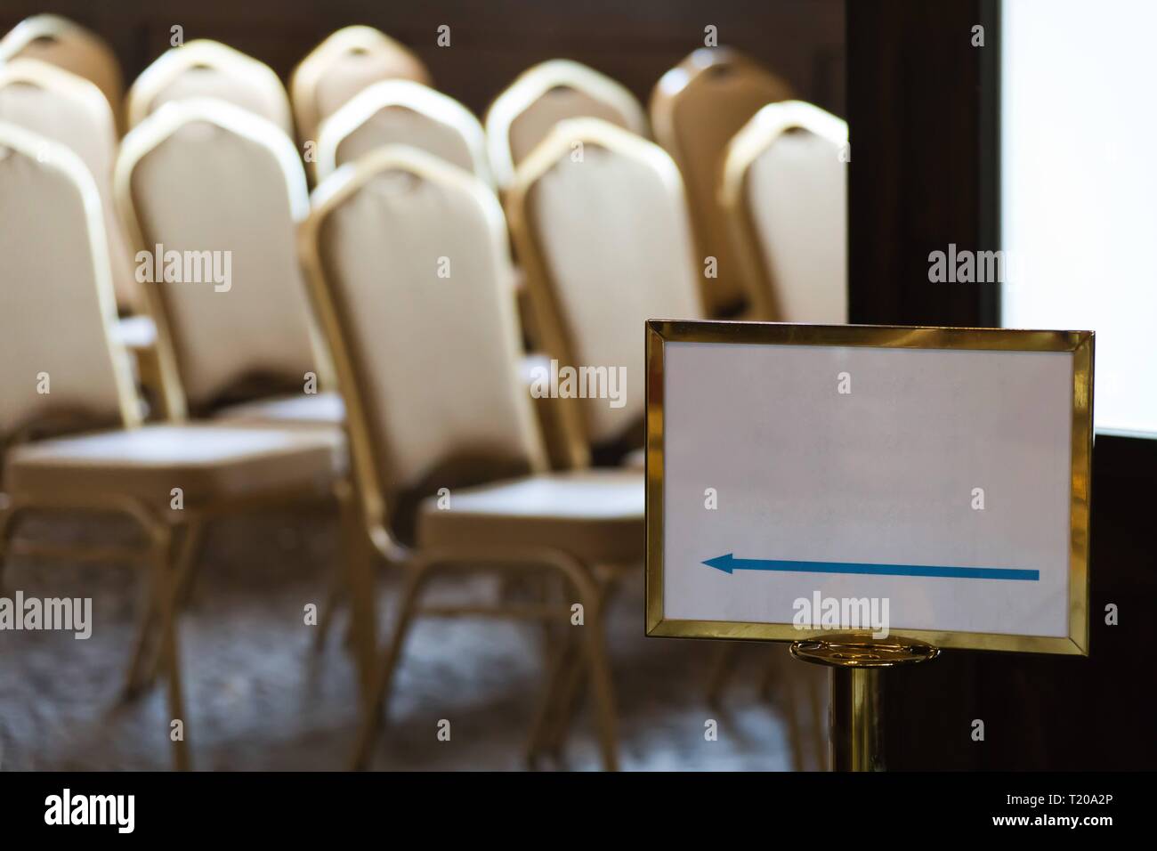 Empty chairs in congress room before seminar, arrow on info panel ...