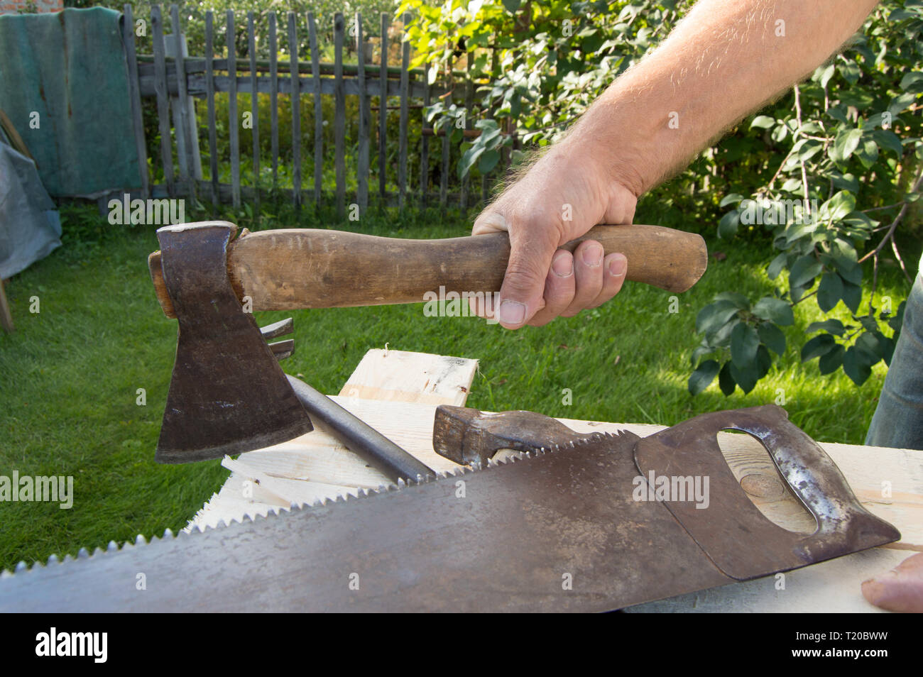 man holding the axe, working with construction tools in his garden ...