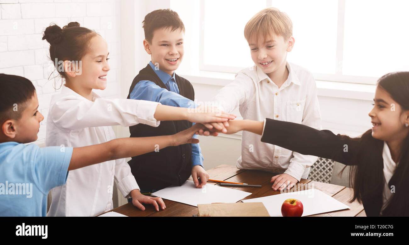 Unity concept. School children putting their hands together at school ...