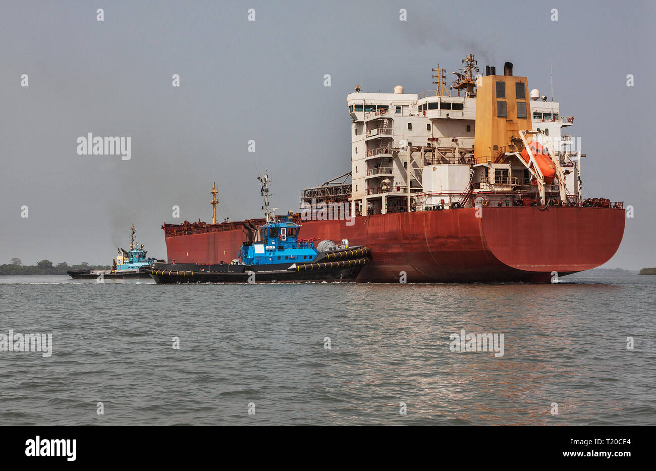 Port operations for managing and transporting iron ore.Tugs manoeuvring ...