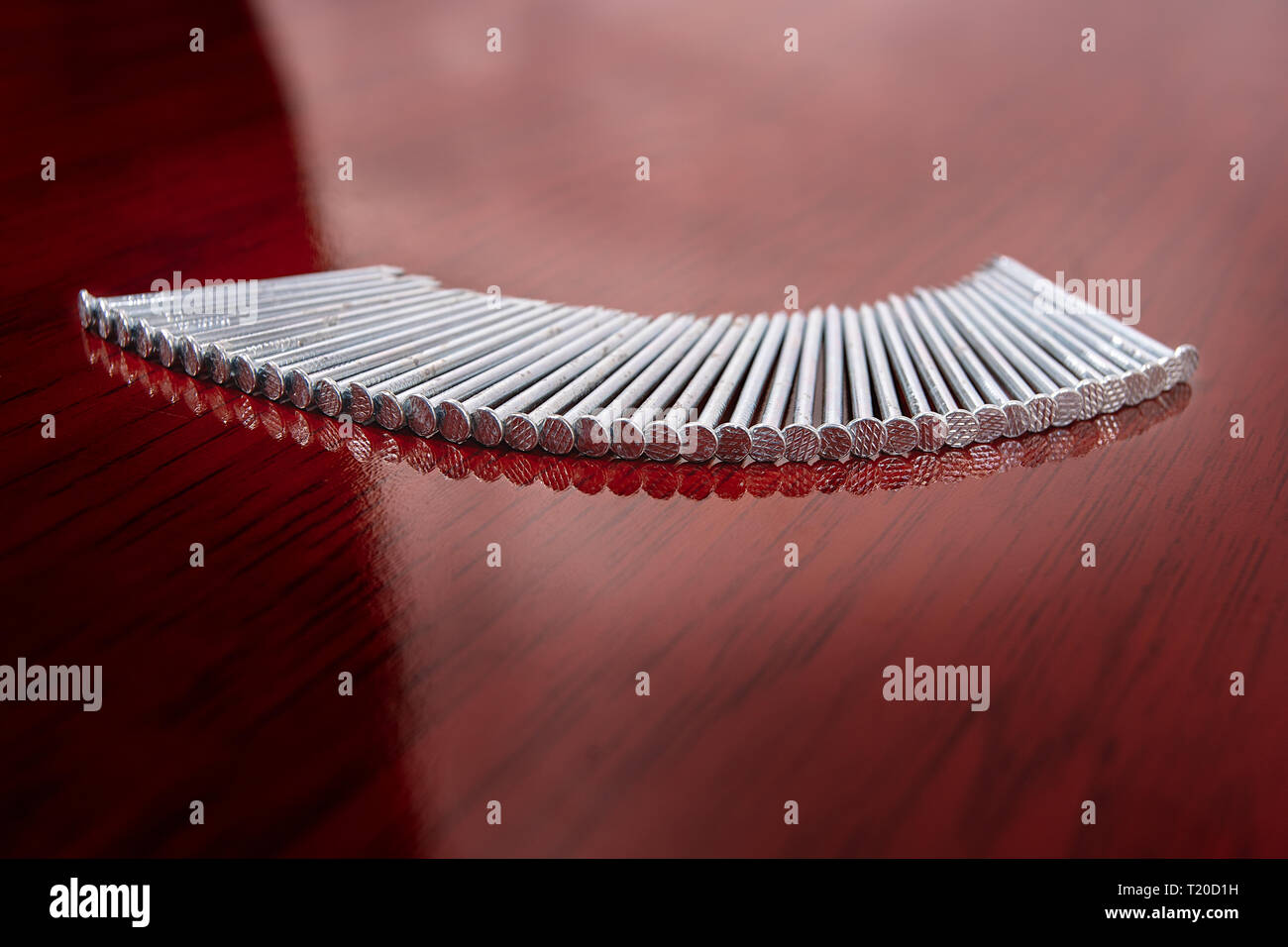 A row of nails on a surface with wooden finish Stock Photo - Alamy