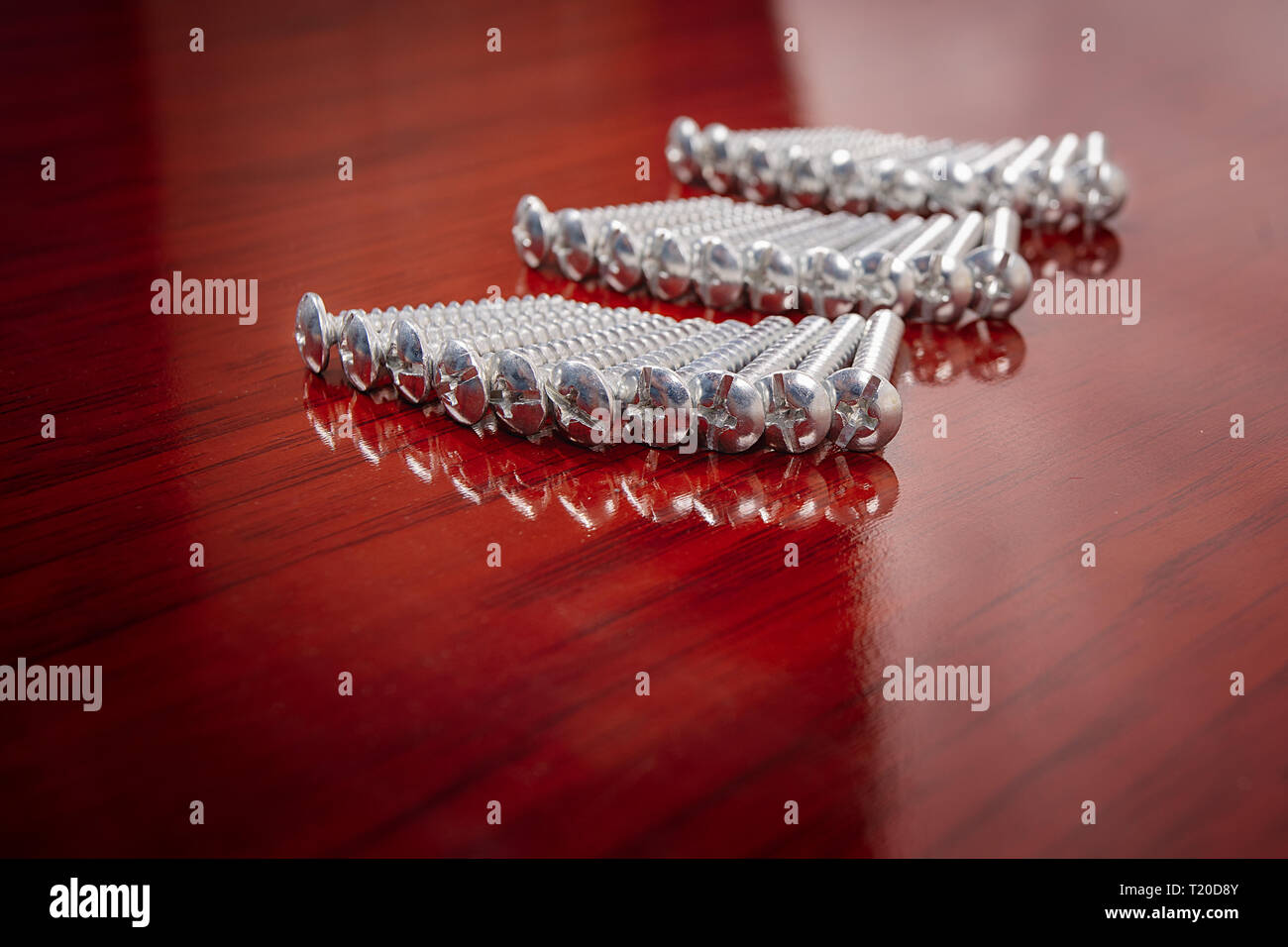Three groups of silver screws arranged in rows on a surface with wooden ...