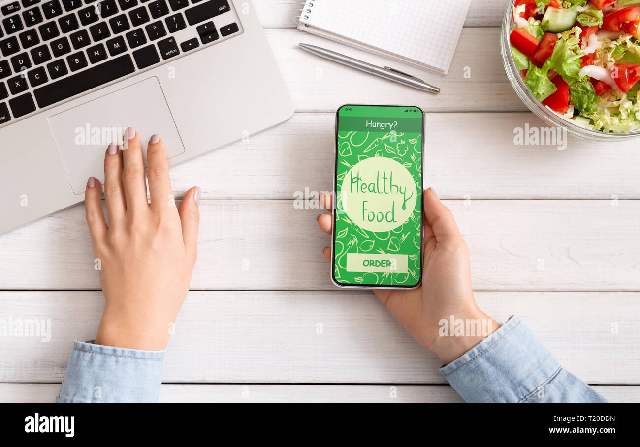 Lunch delivery. Woman using laptop and mobile phone with healthy food ...