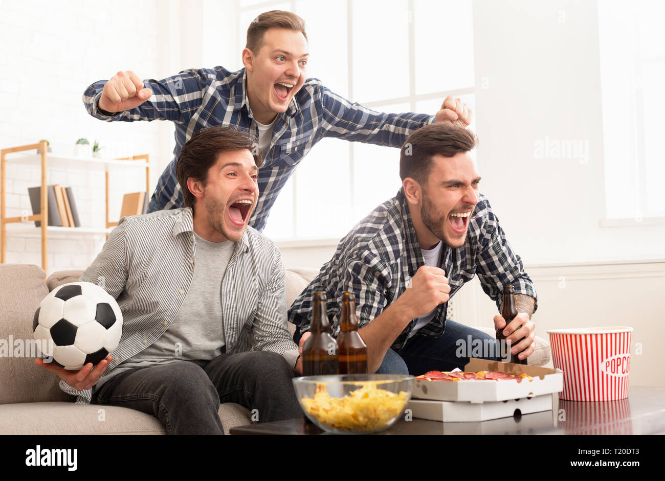 Excited friends watching football match and shouting, cheering for ...