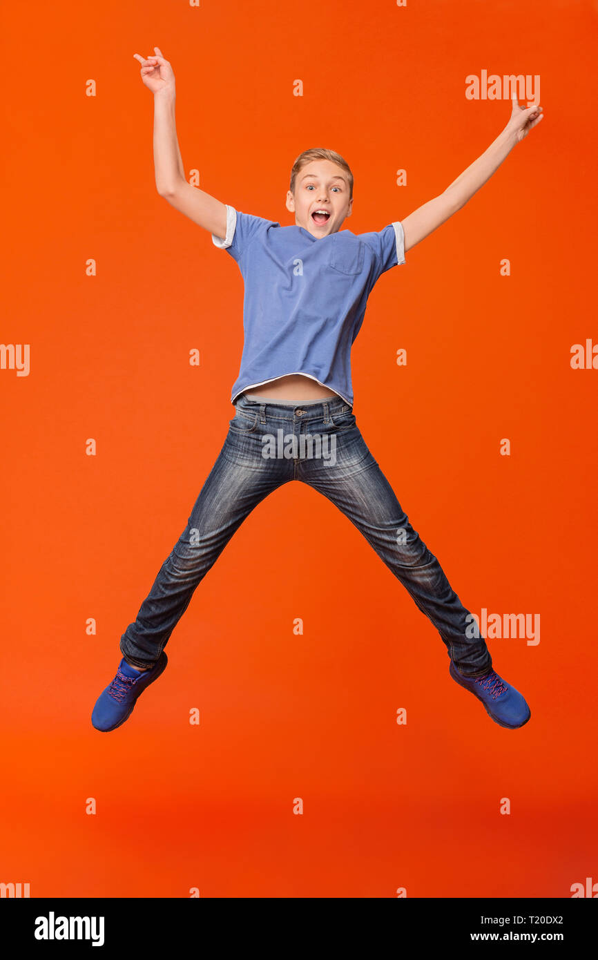 Adorable happy boy jumping and raising his hands up in air. orange ...