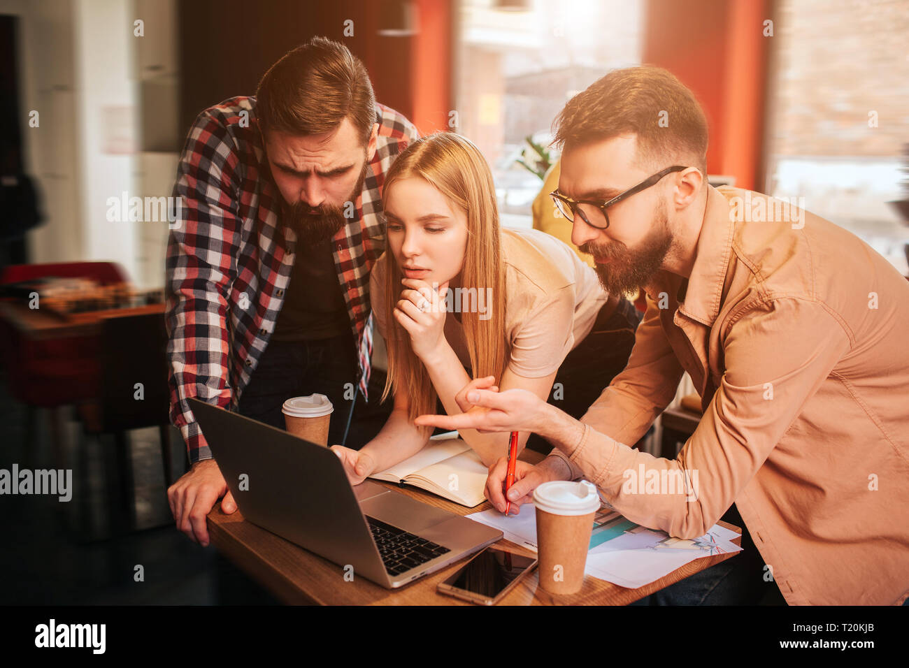 Three best friends are standing near table with computer on it and ...