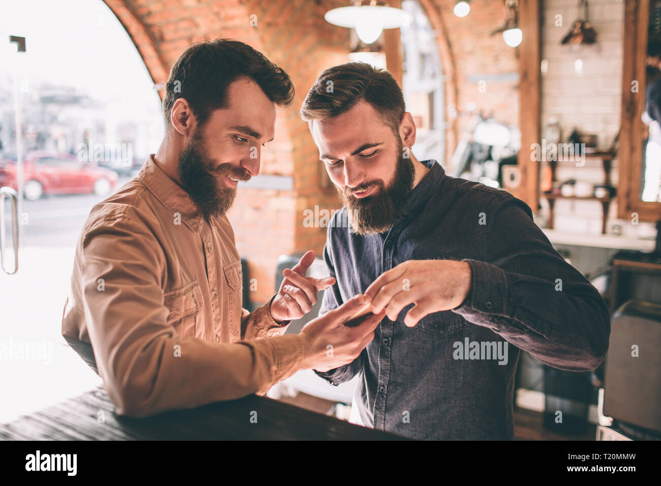 Two happy friends are in a barbershop. They are standing together and ...