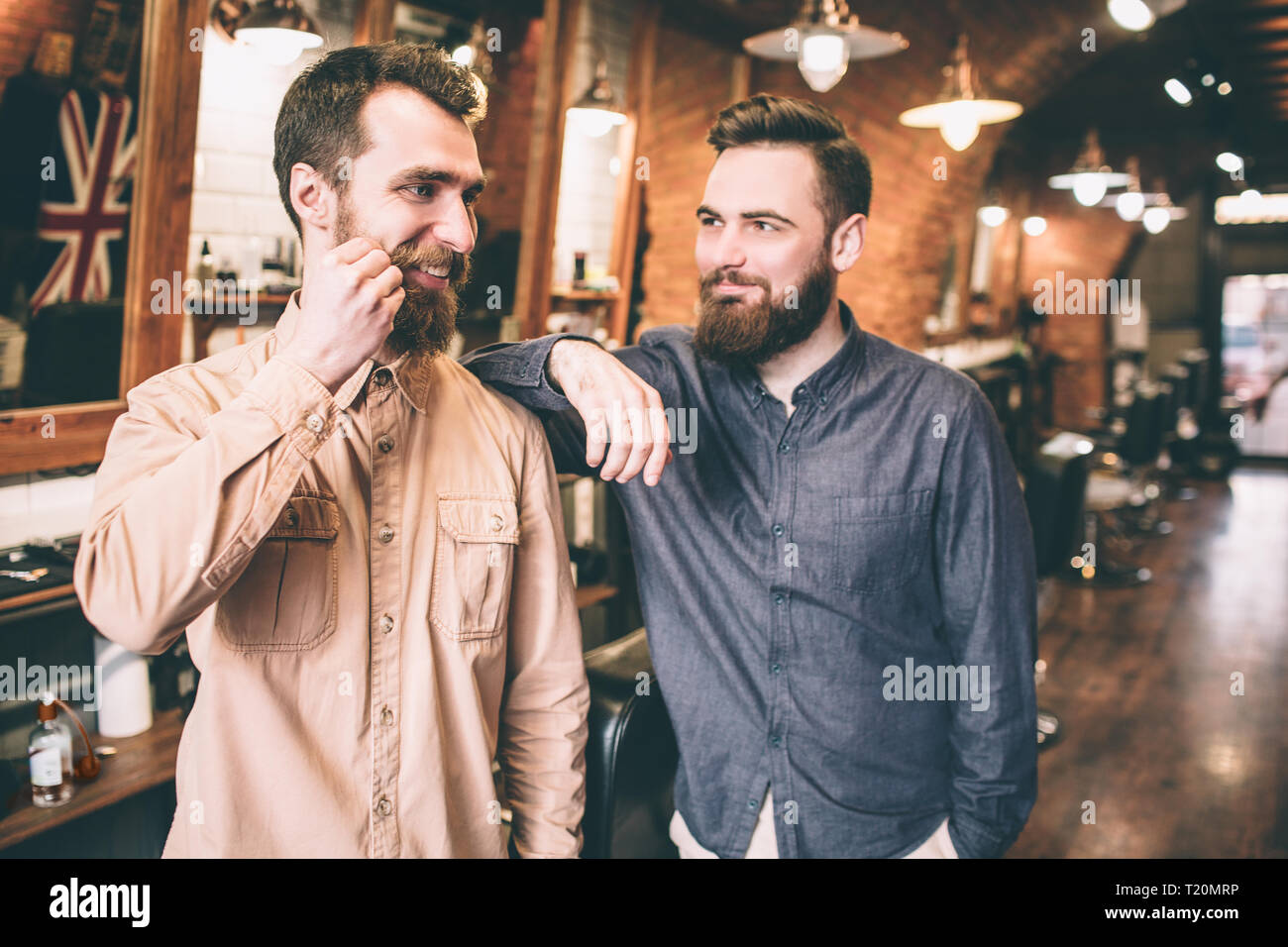 Happy guy is touching his new moustache with his hands. His friend is ...
