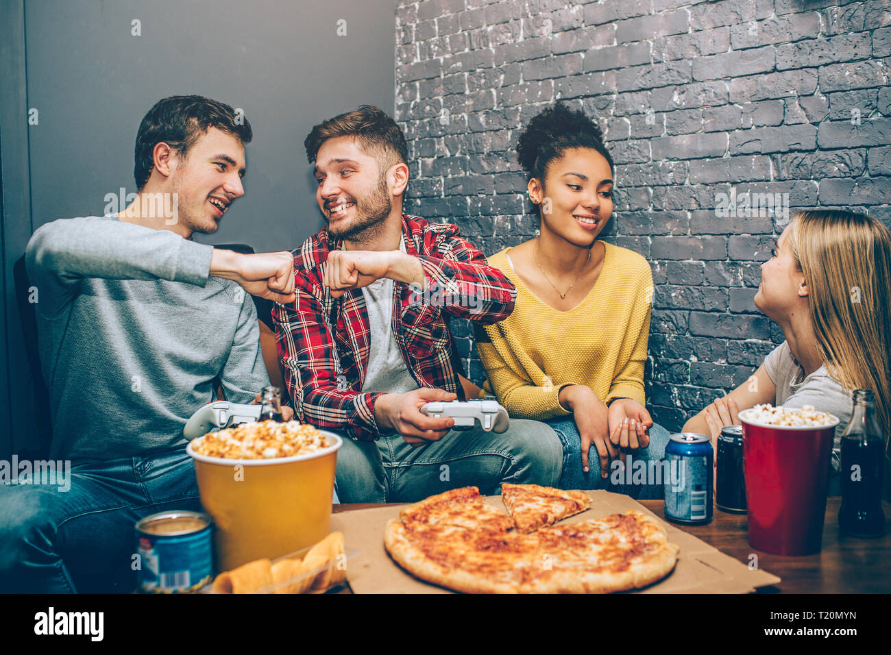 Friends sitting around table in grey room and spending some time ...