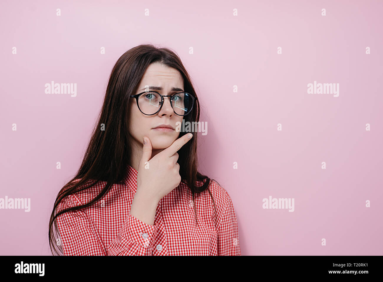 Serious contemplative woman holds chin, looks with thoughtful ...