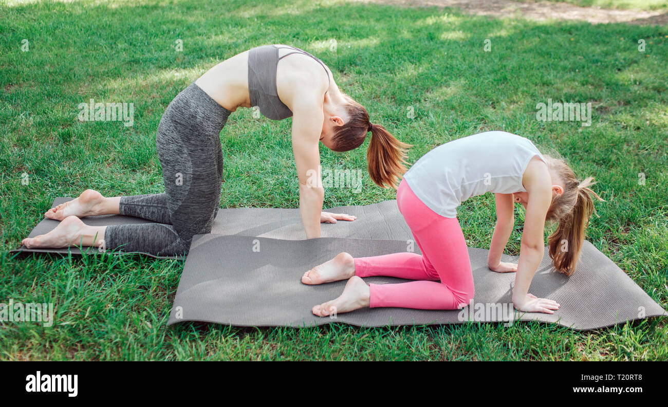 Two girls are standing on carimate and holding their back curved. They ...