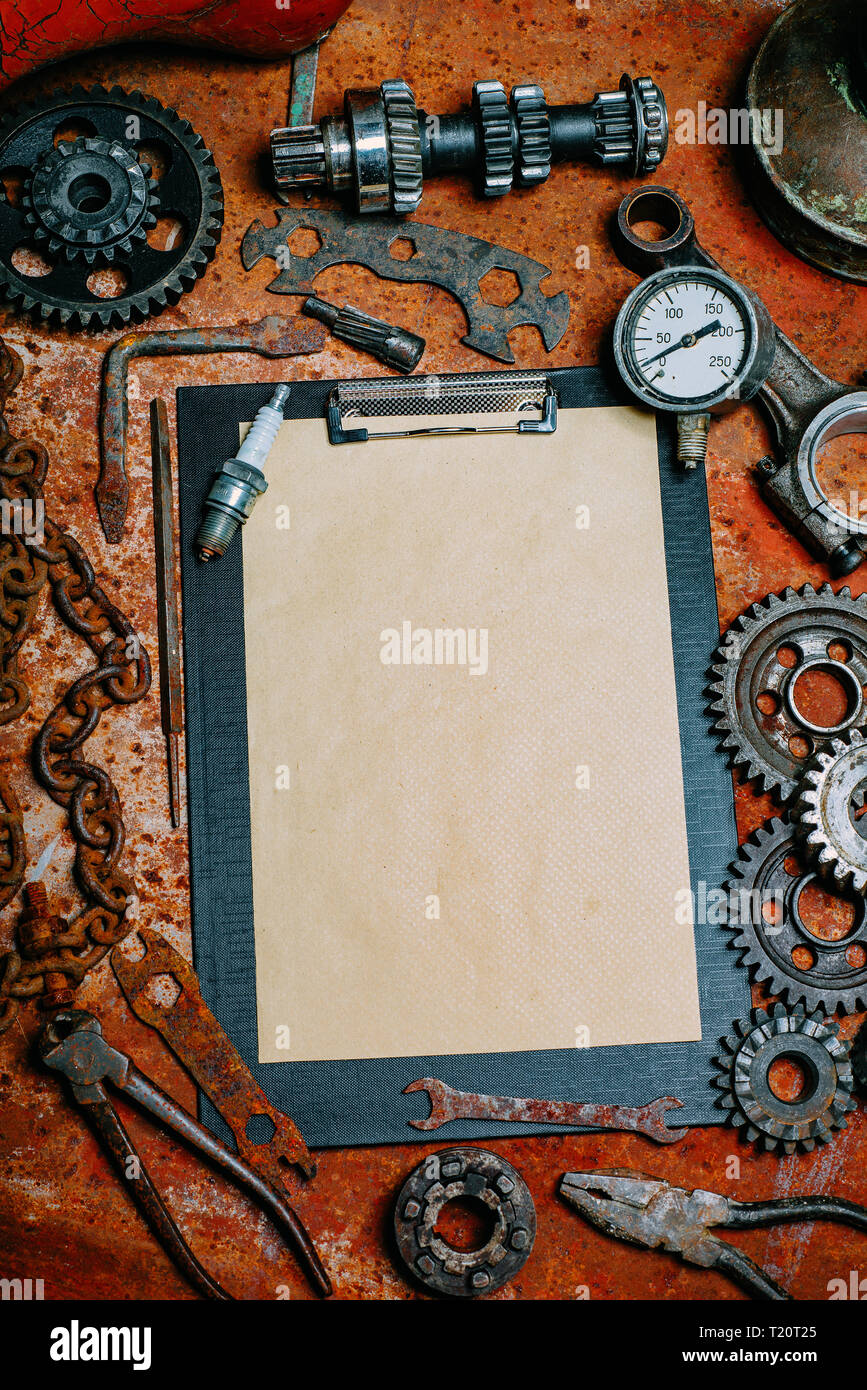 Clipboard with vintage paper in the center of rusty tools, gears on old ...