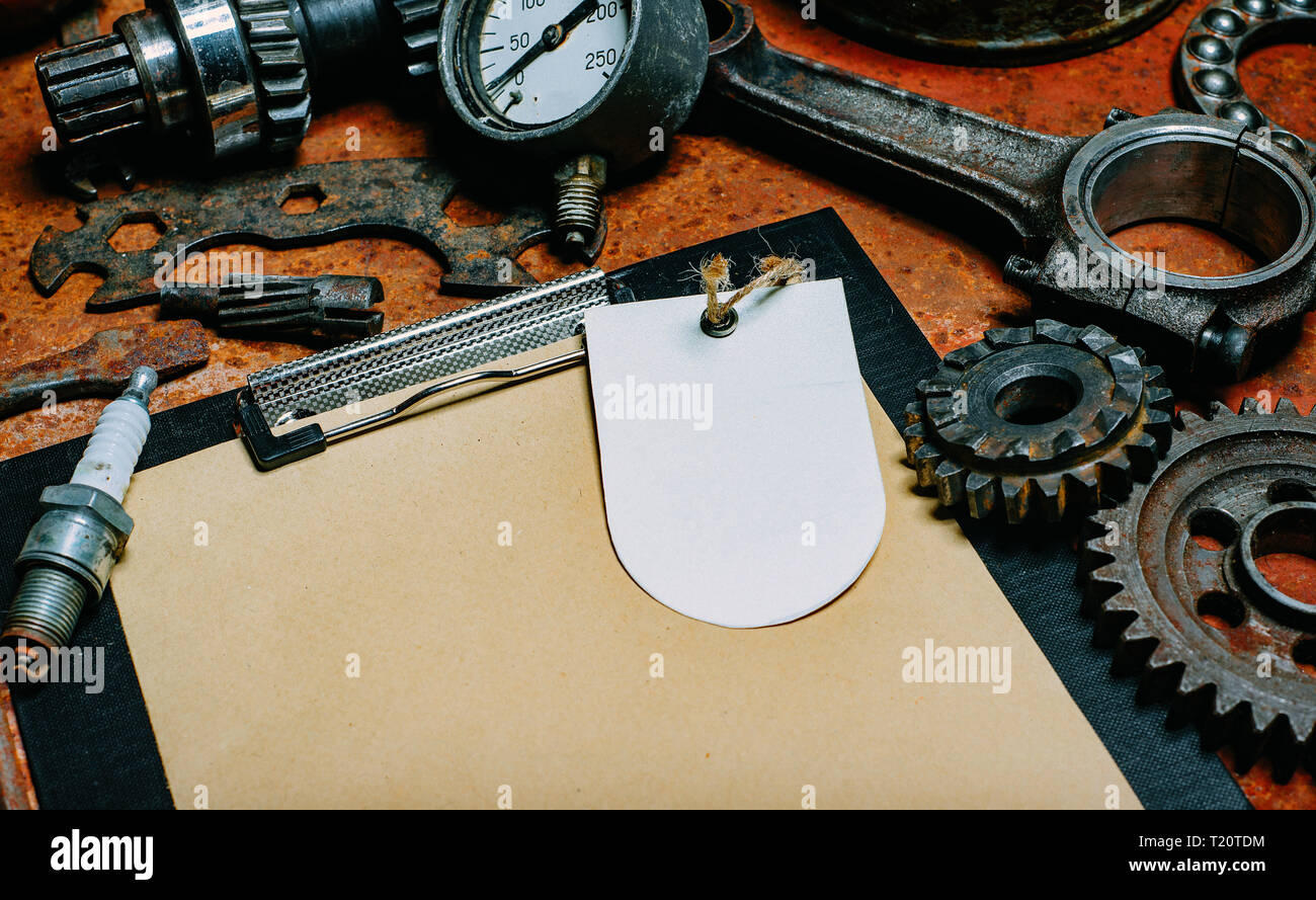 Part of closeup clipboard with paper and label. Rusty tools, gears ...
